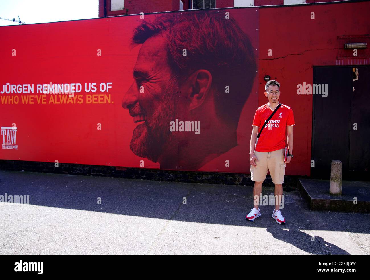A Liverpool fan poses for a photo in front of an image of Jurgen Klopp ...