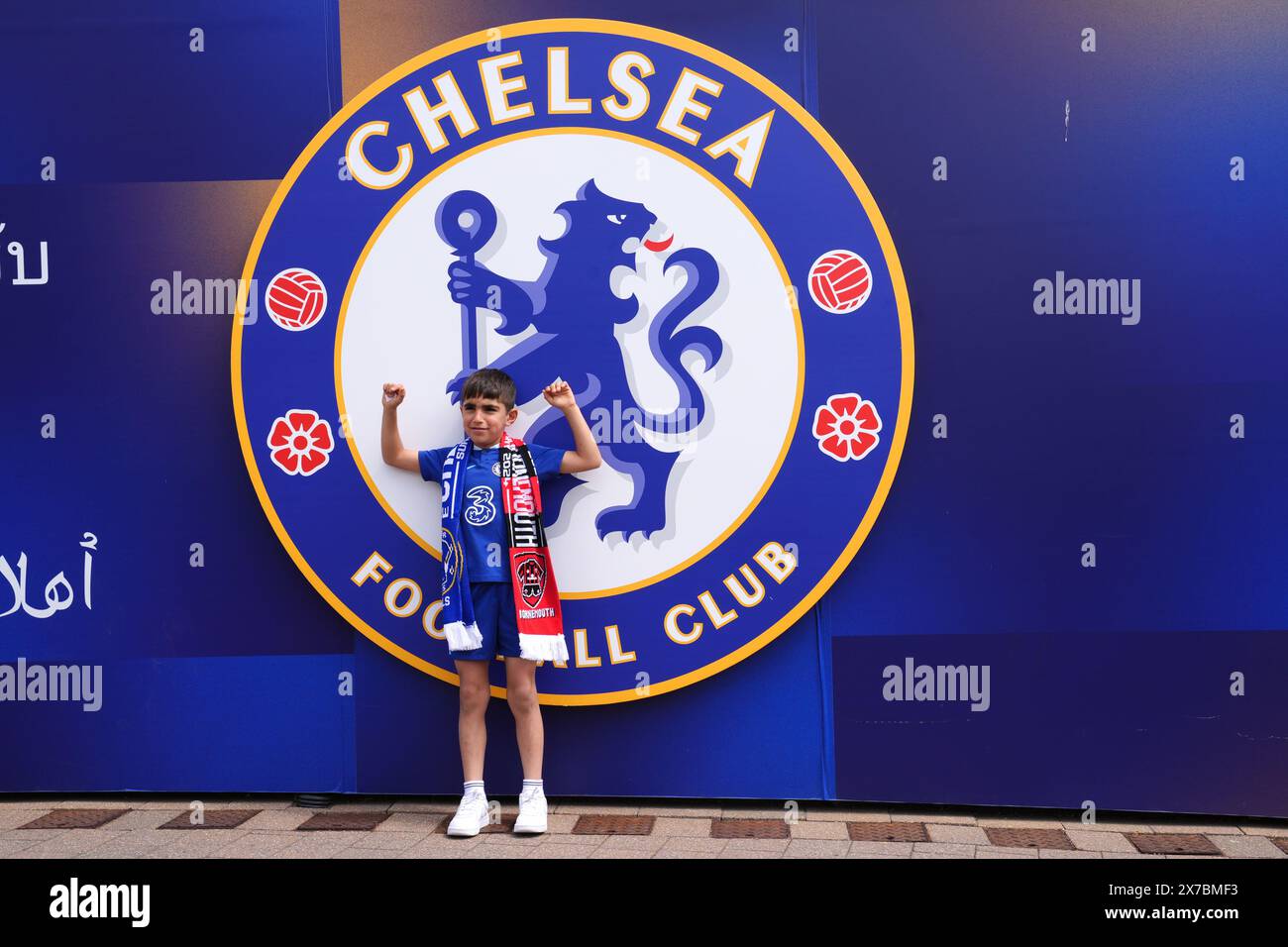A young Chelsea fan stands in front of a large crest of the club before ...