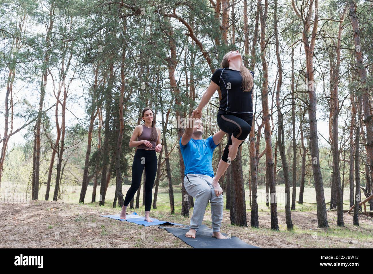 Three friends practice acro yoga exercises while hiking in the forest ...