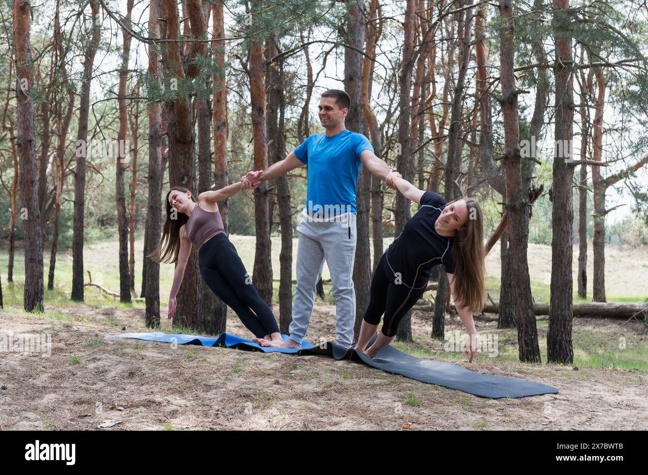 Three friends practice acro yoga exercises while hiking in the forest ...