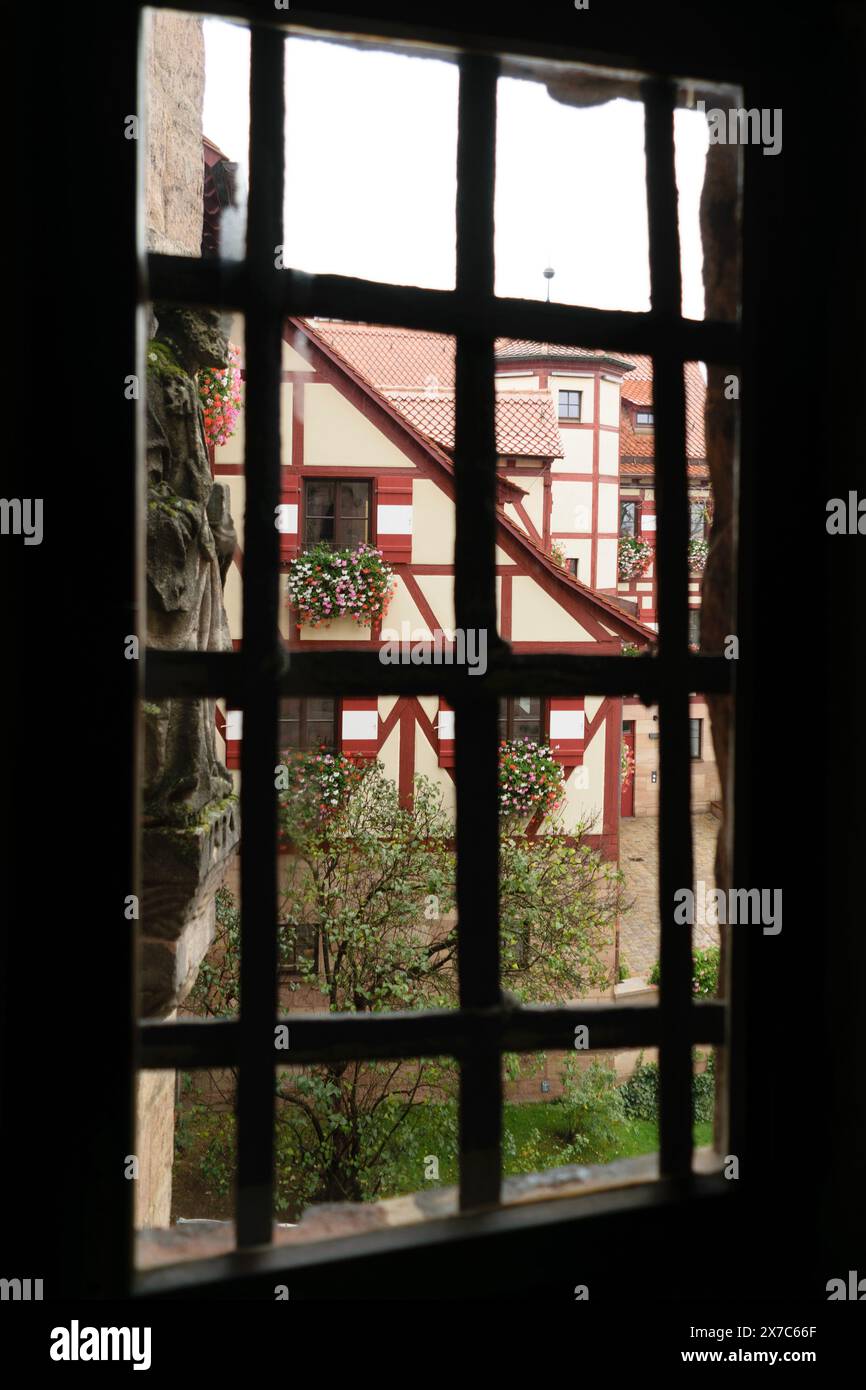 View through a window with bars, showing a traditional half-timbered ...