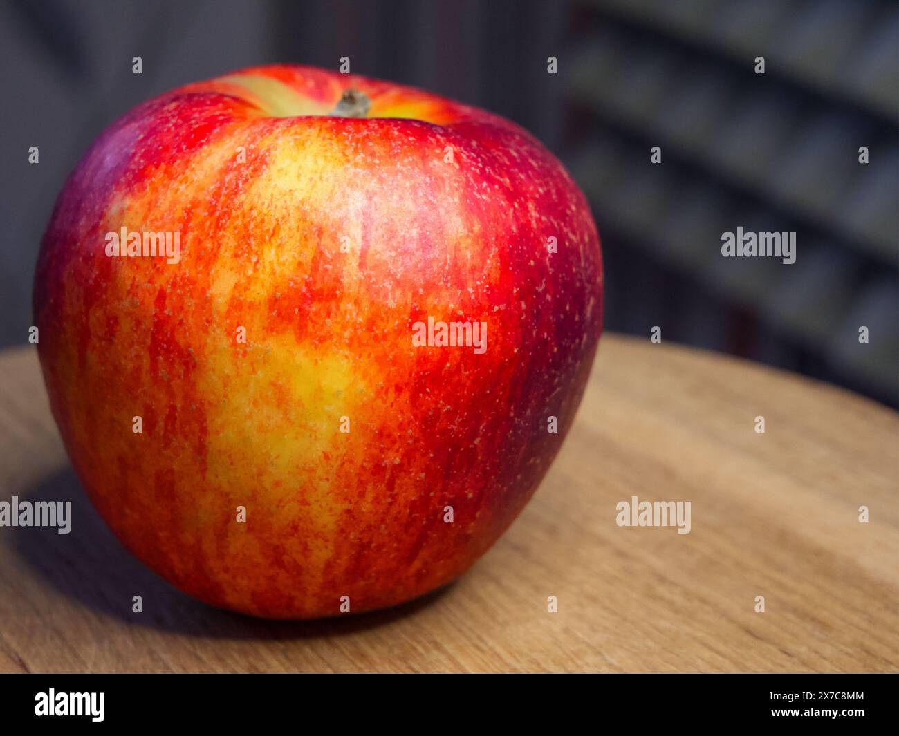 Vibrant red apple, stem intact, water droplets, wooden surface, grey ...