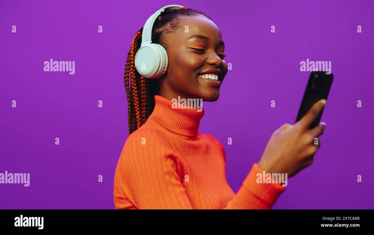 Gen Z woman with vibrant braids stands against a purple background ...