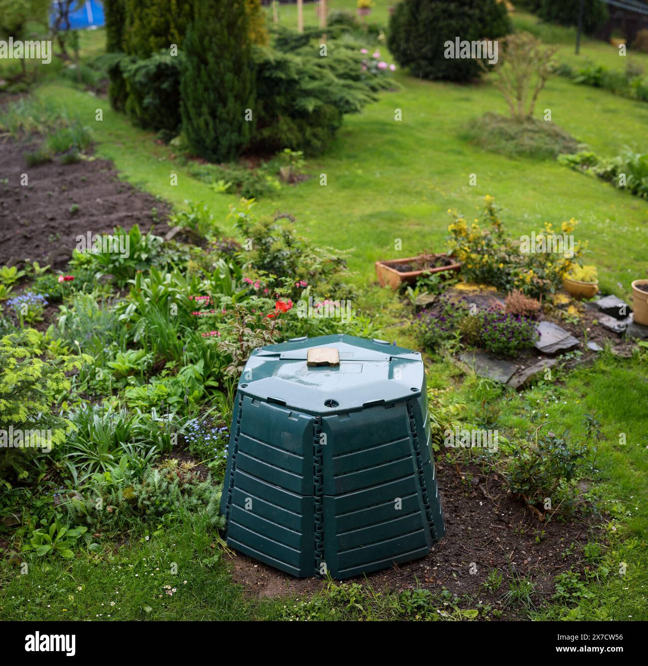 Outdoor composting bin for recycling kitchen and garden organic waste in a lovely lush garden ...