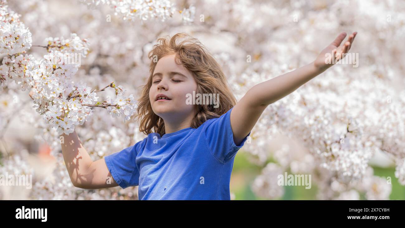 Kid in spring cherry blossom park. Peaceful kid with raised hands ...