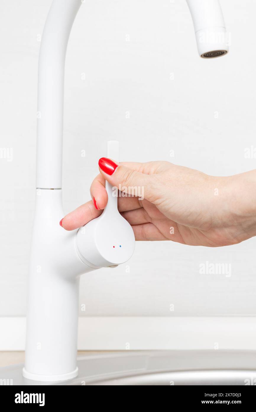 female hand turns the selector on the kitchen faucet. hand turns the ...