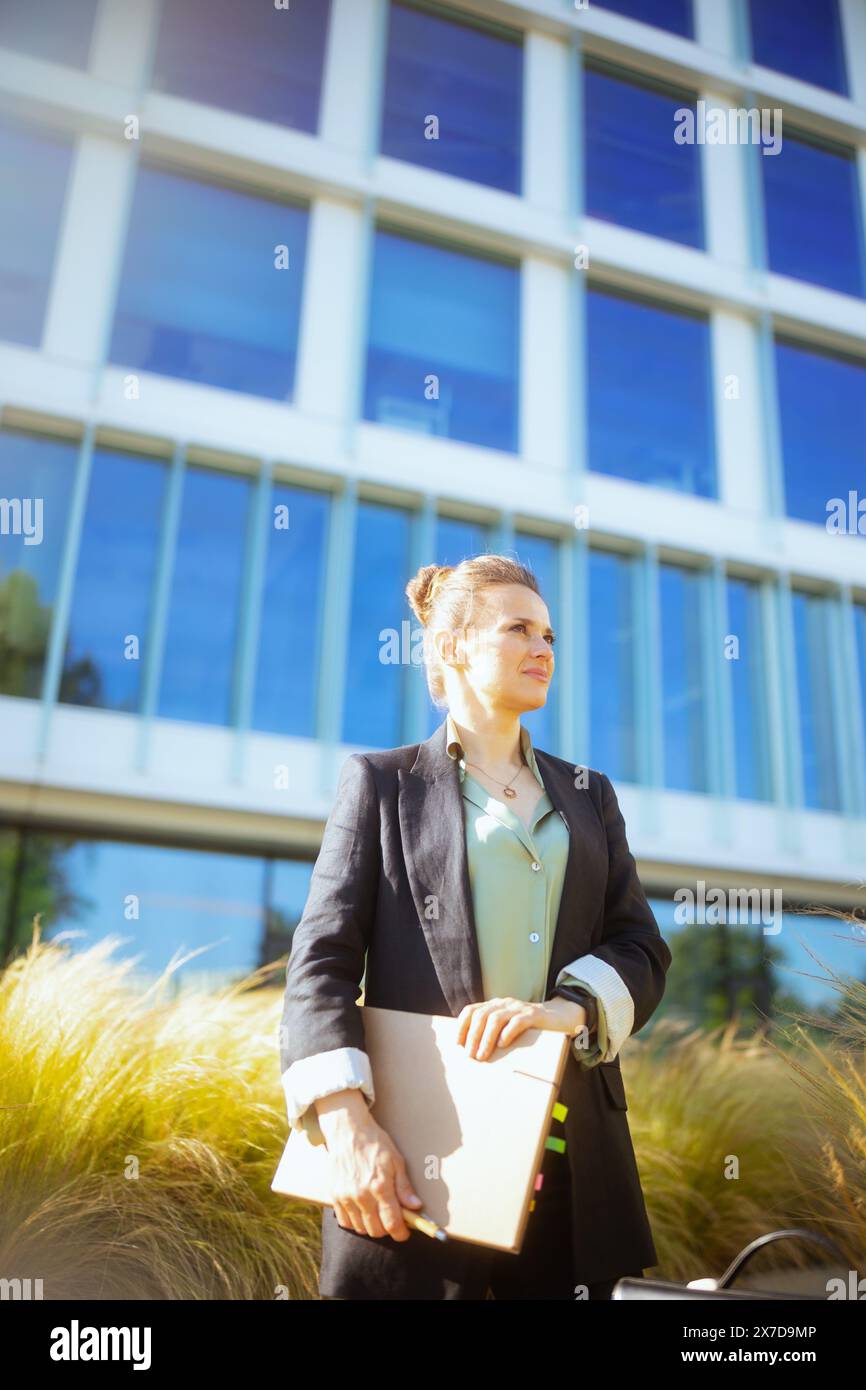 pensive modern female employee near office building in black jacket ...