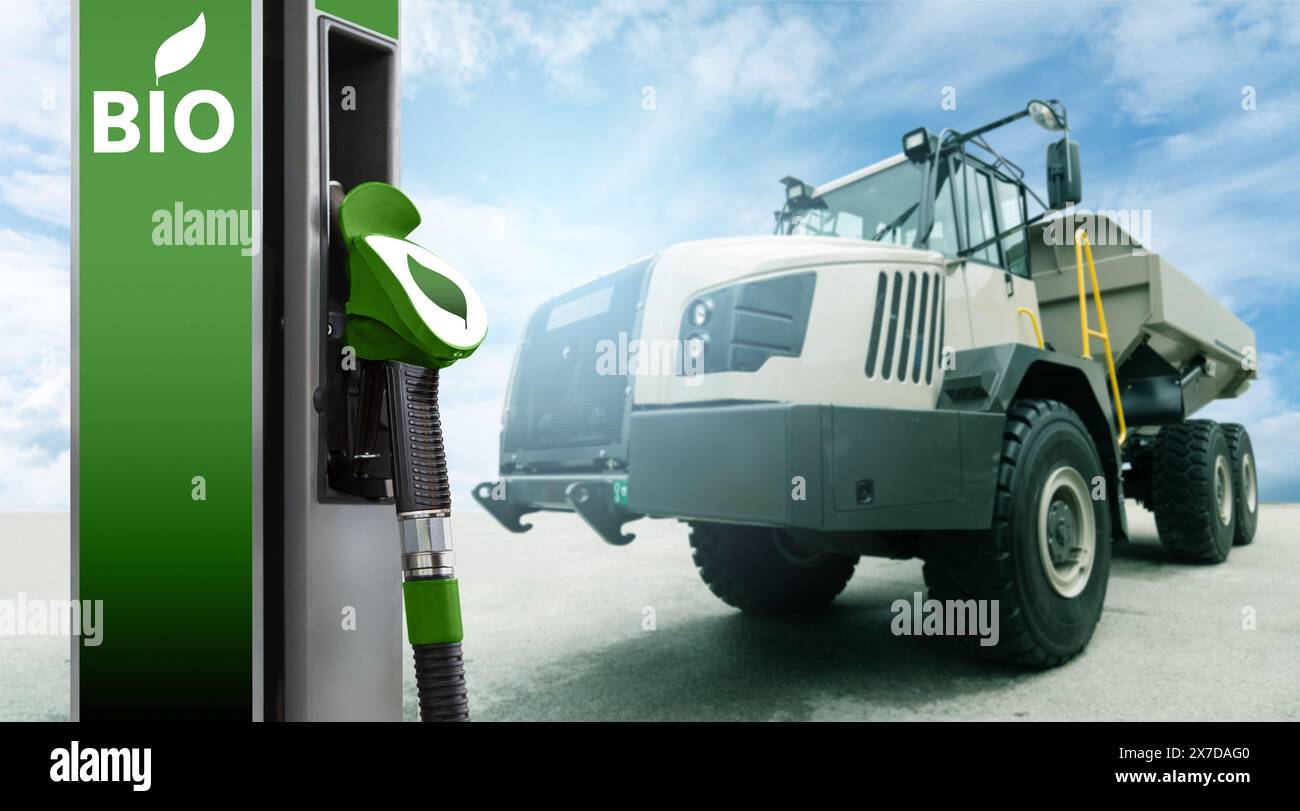 Hand with biofuel filling nozzle on a background of mining truck ...