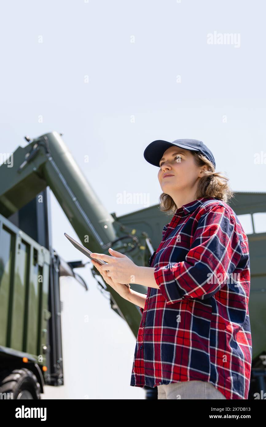 Woman farmer with tablet watching grain loading Stock Photo - Alamy