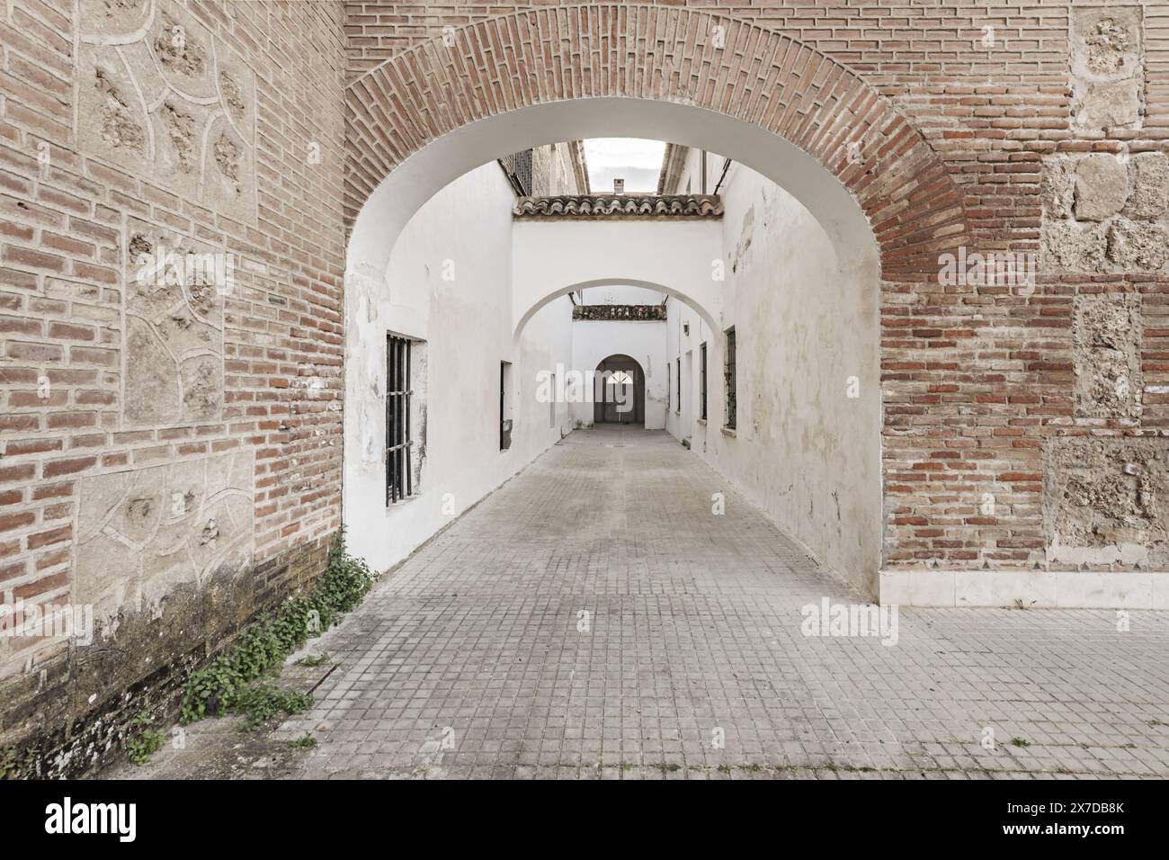 A passageway with whitewashed walls in a monumental building with brick ...