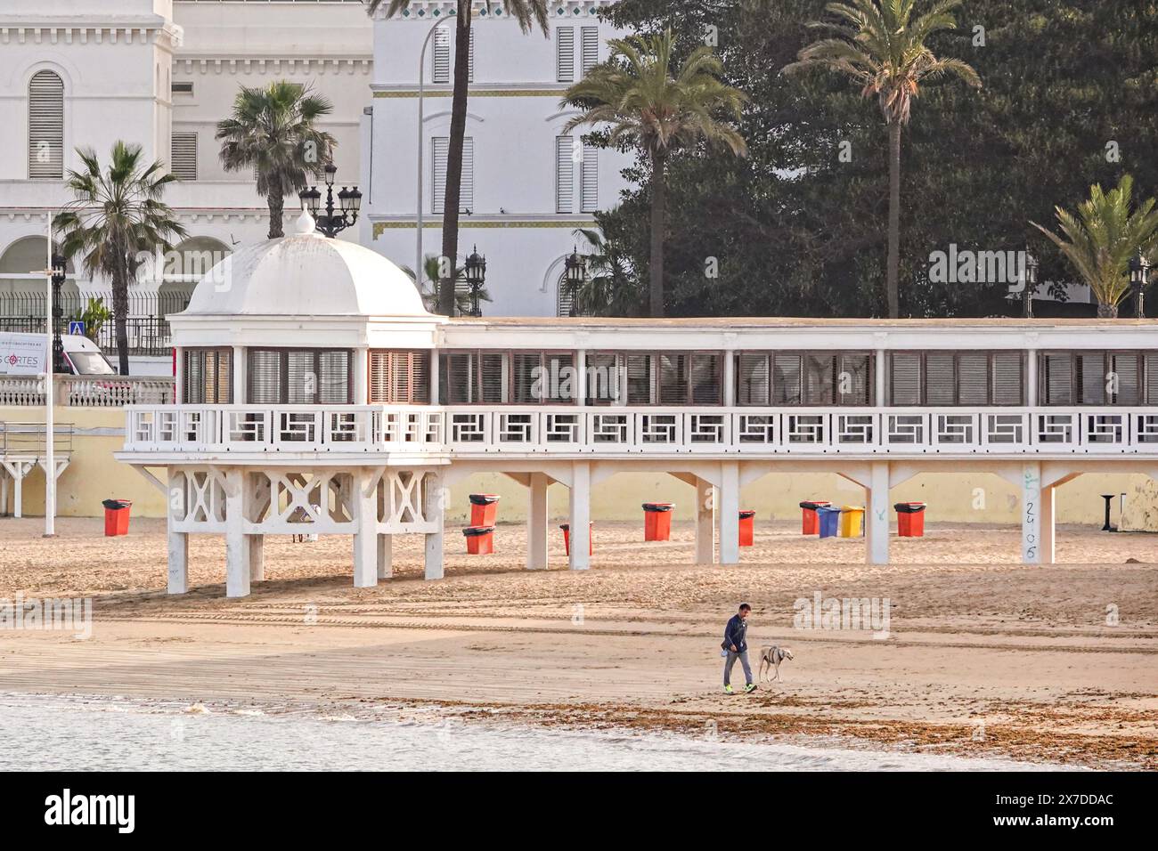 A man walks his dog on the beach by the moorish style hexagonal ...