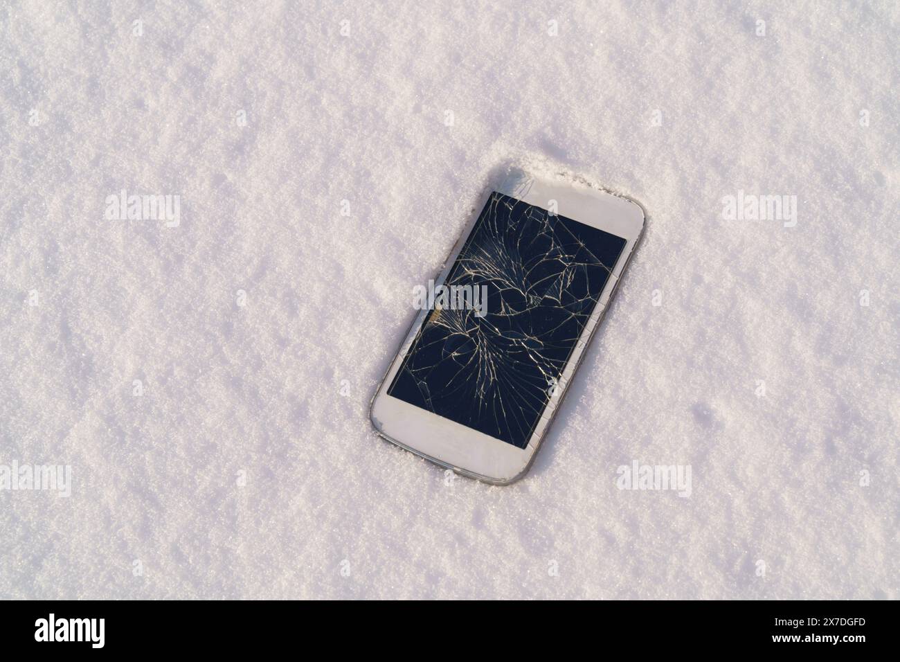 Broken mobile phone with cracked display over natural snow background ...