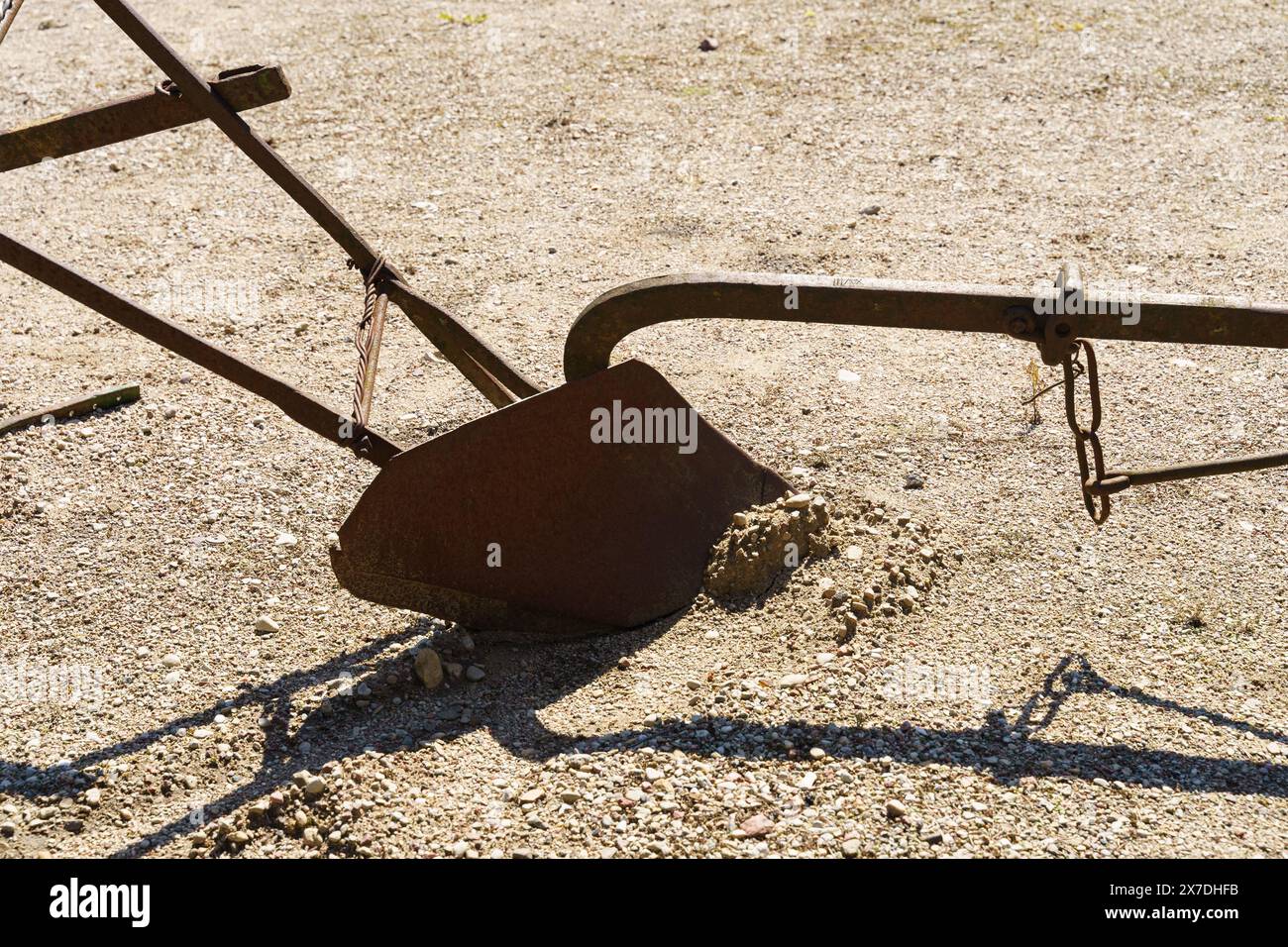 A close-up view of an old, rusty plow blade with its shadow cast on the ...