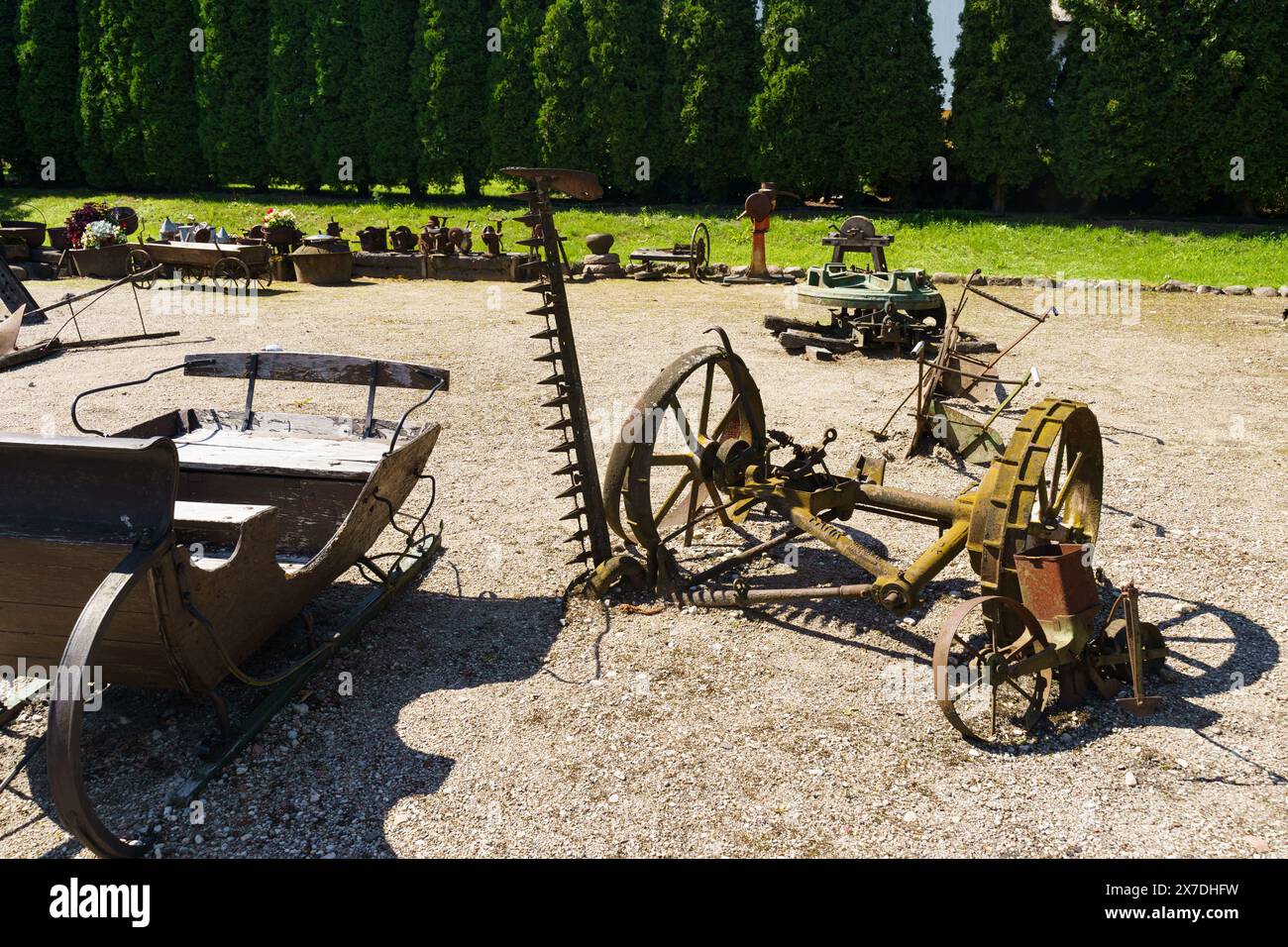 Two farm implements, a plow and a harrow, are seen resting on a dirt ...