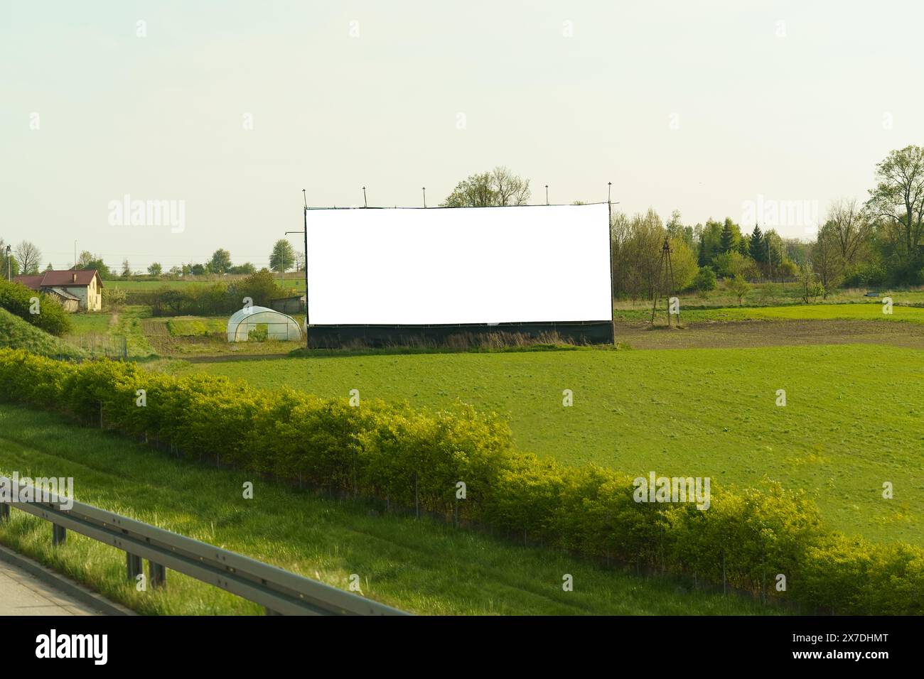 A big LED screen stands tall amidst a vast green field, creating a ...