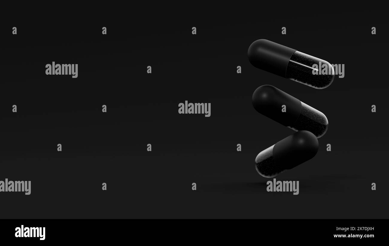 Three black capsules, pills with black granules inside float on black ...