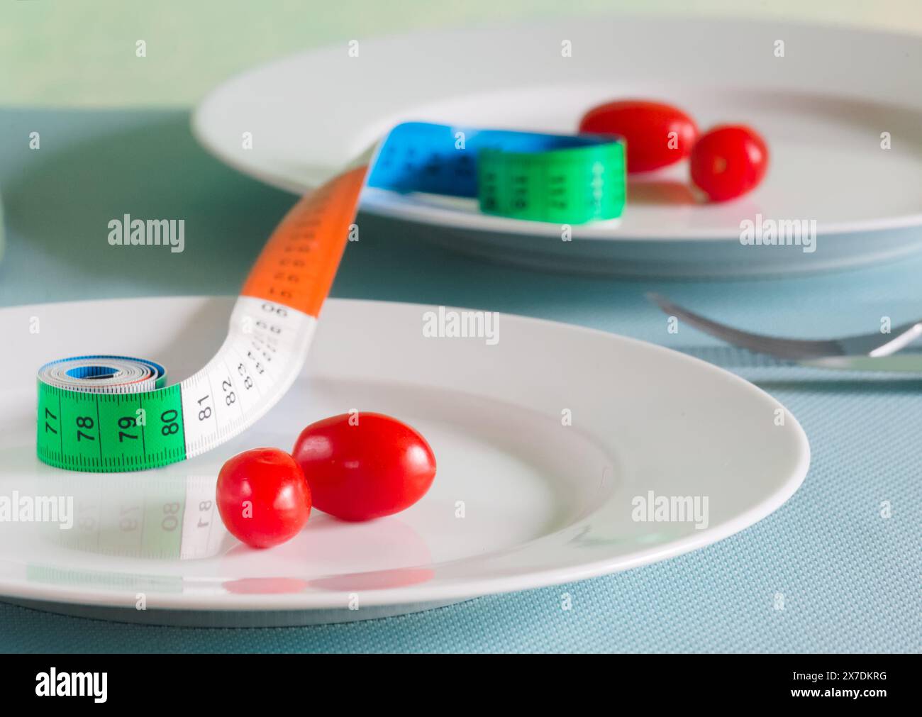 two plates with small tomatos and a tape measure, dieting,reducing ...
