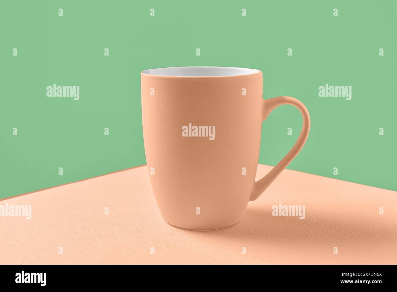 A mug of apricot crush color on Dark Green Tea color paper background ...
