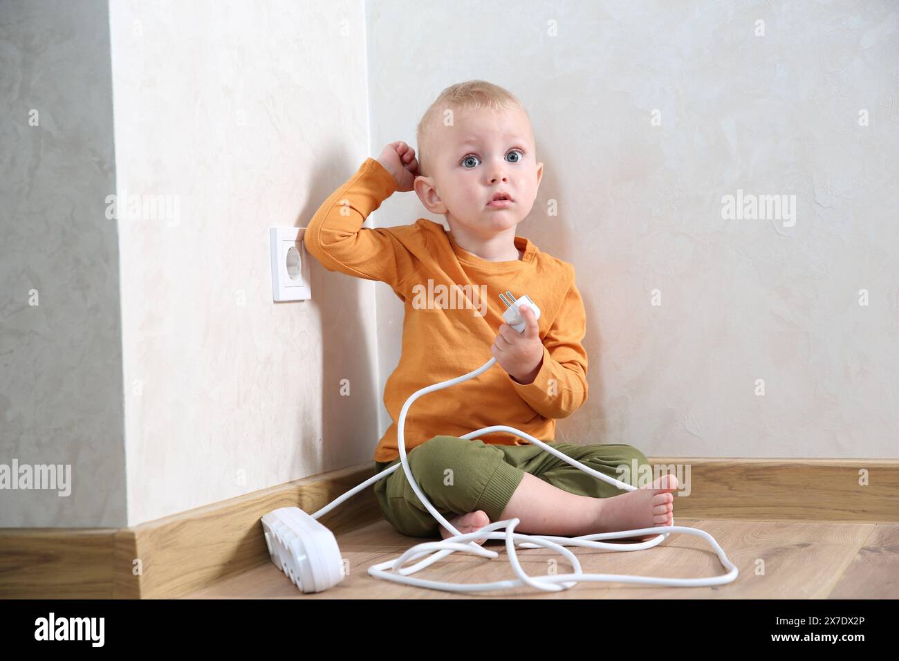 Little child playing with power strip plug near electrical socket at ...
