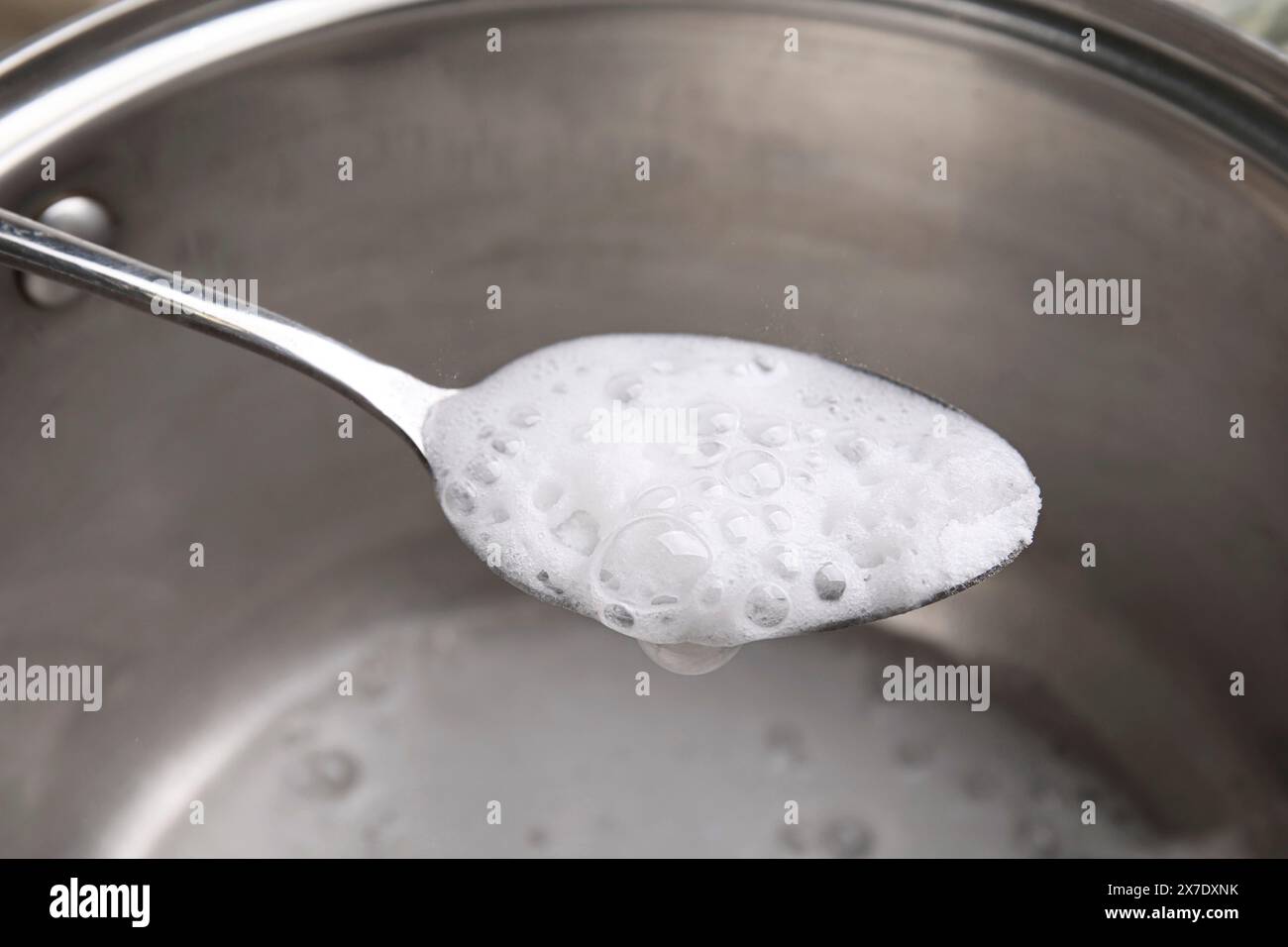 Chemical reaction of vinegar and baking soda in spoon over saucepan ...