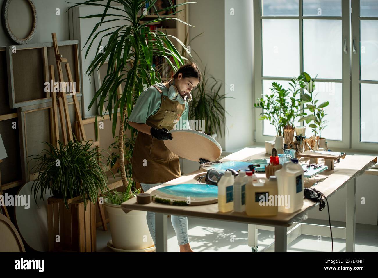 Craftswoman artist examining finished acrylic sea painting on round ...