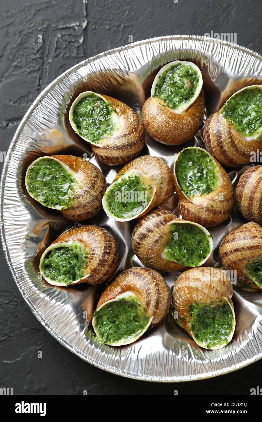 Delicious cooked snails on dark textured table, top view Stock Photo ...