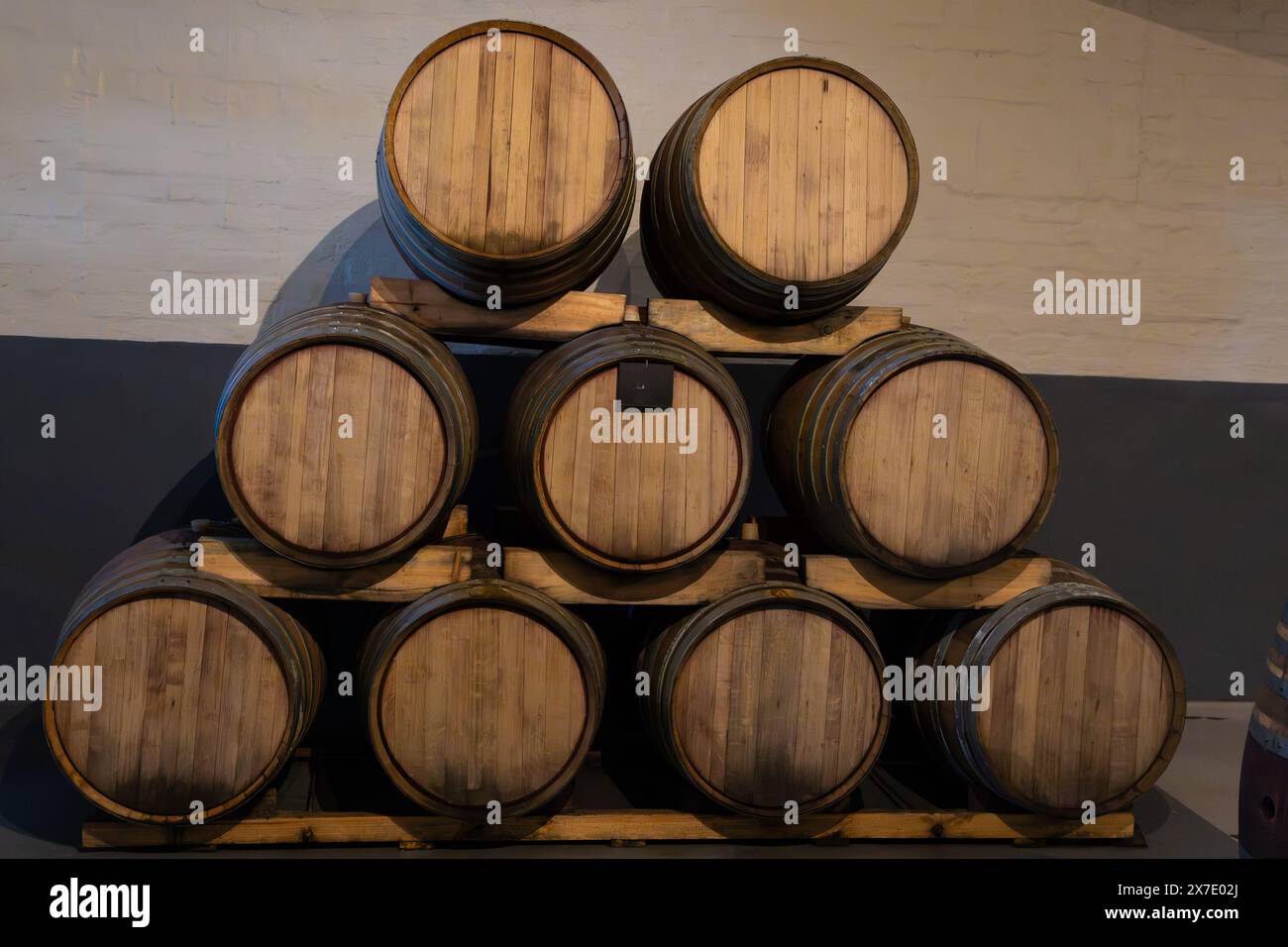Wooden oak wine barrels in a cellar stacked on top of each other in a ...