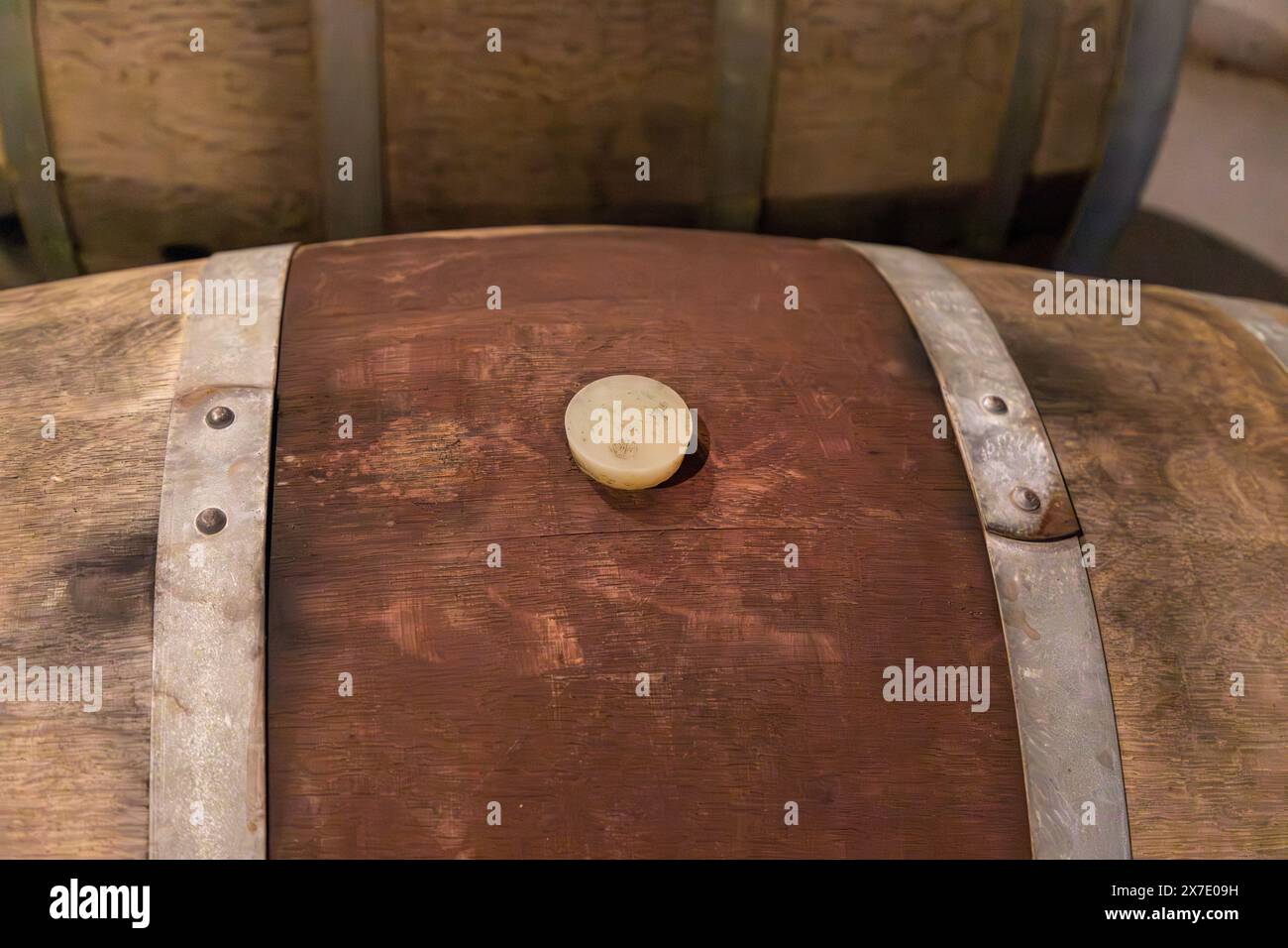 Close up on the top of an old wooden oak barrel with wine. Center is ...
