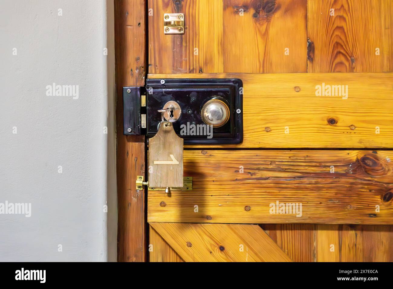 Wooden door with an old handle and locking mechanism. Key in the lock ...