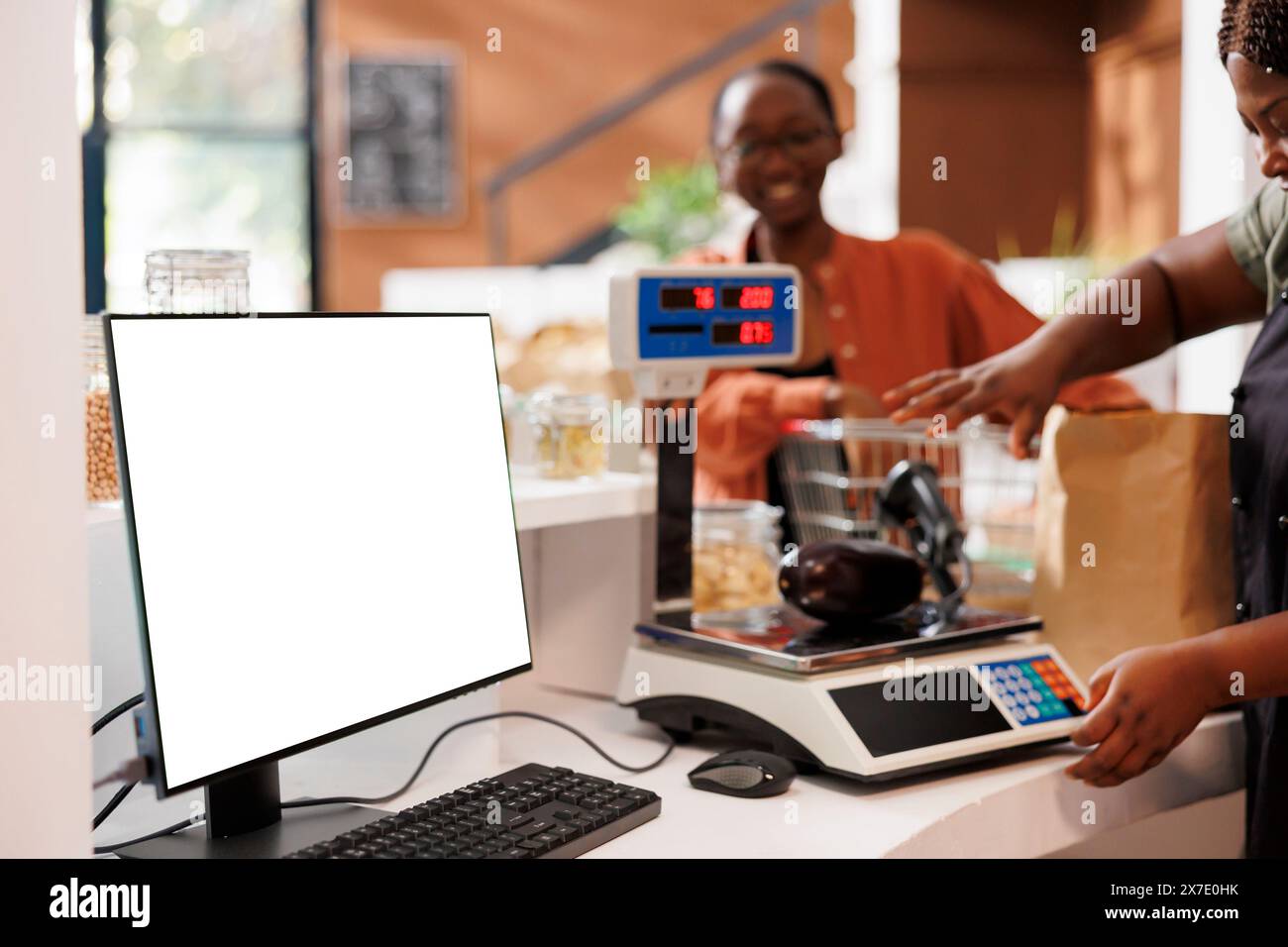 Seller using scale to measure organic products, with computer screen ...