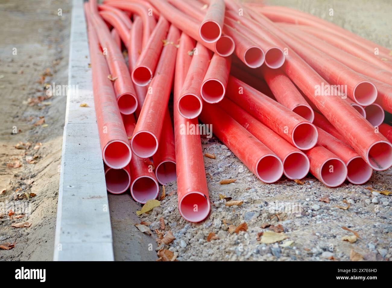 Pile of plastic red water pipes at a construction site. Laying utility ...