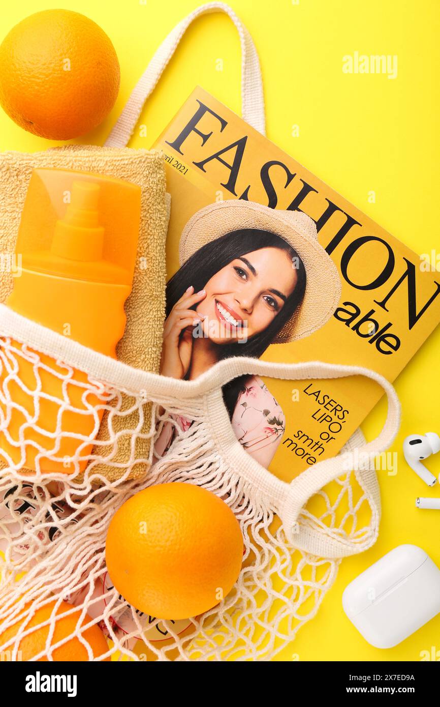 String bag with fresh oranges, fashion magazine and beach accessories ...