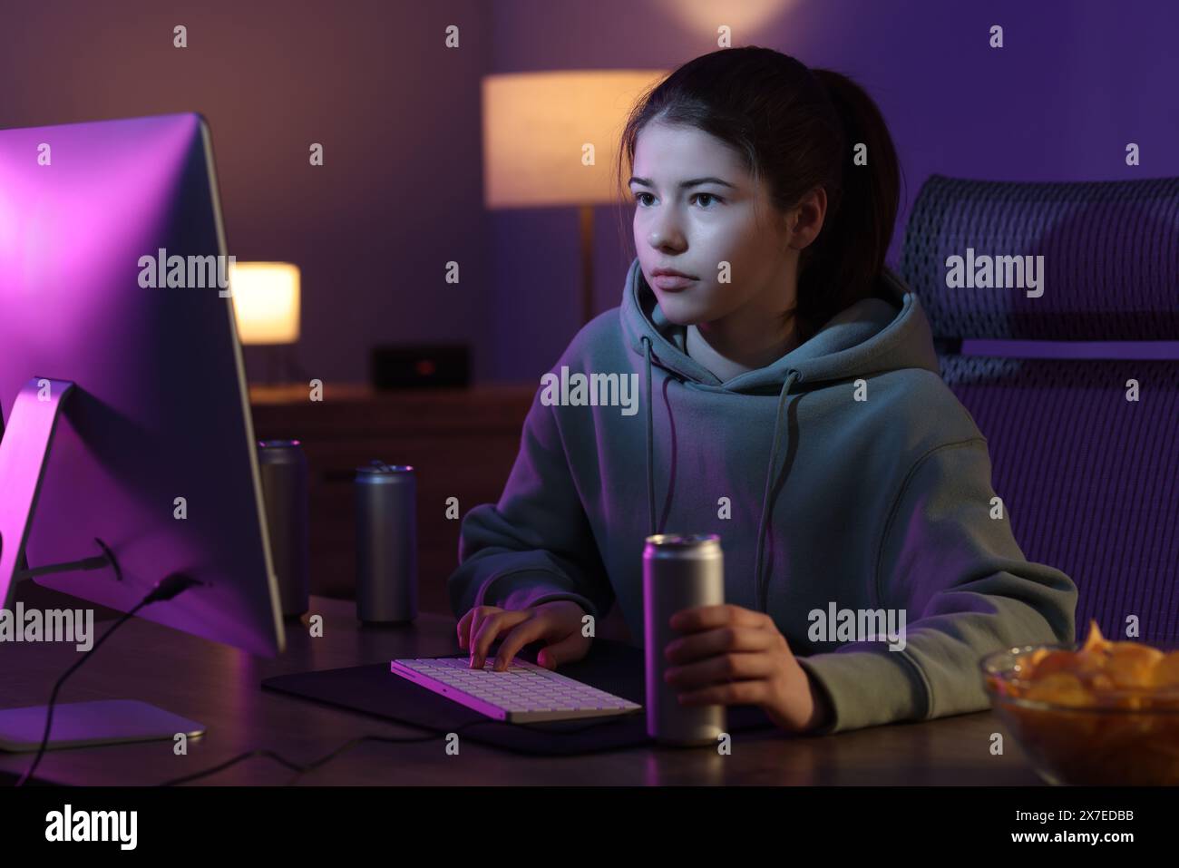 Girl with energy drink playing computer game at table in room Stock ...