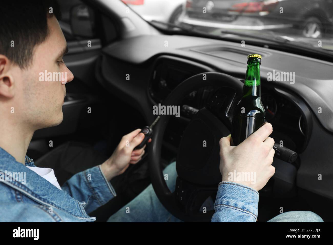 Man with bottle of beer driving car, closeup. Don't drink and drive ...