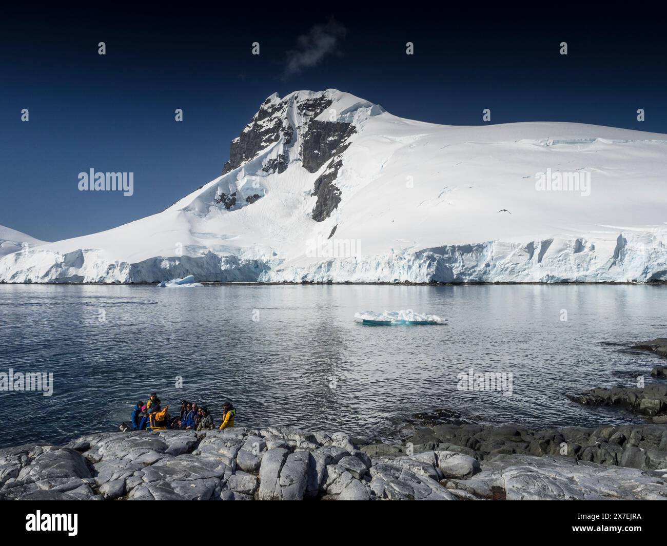 a zodiac full of tourists land at Palaver Point with Buache Peak in the ...