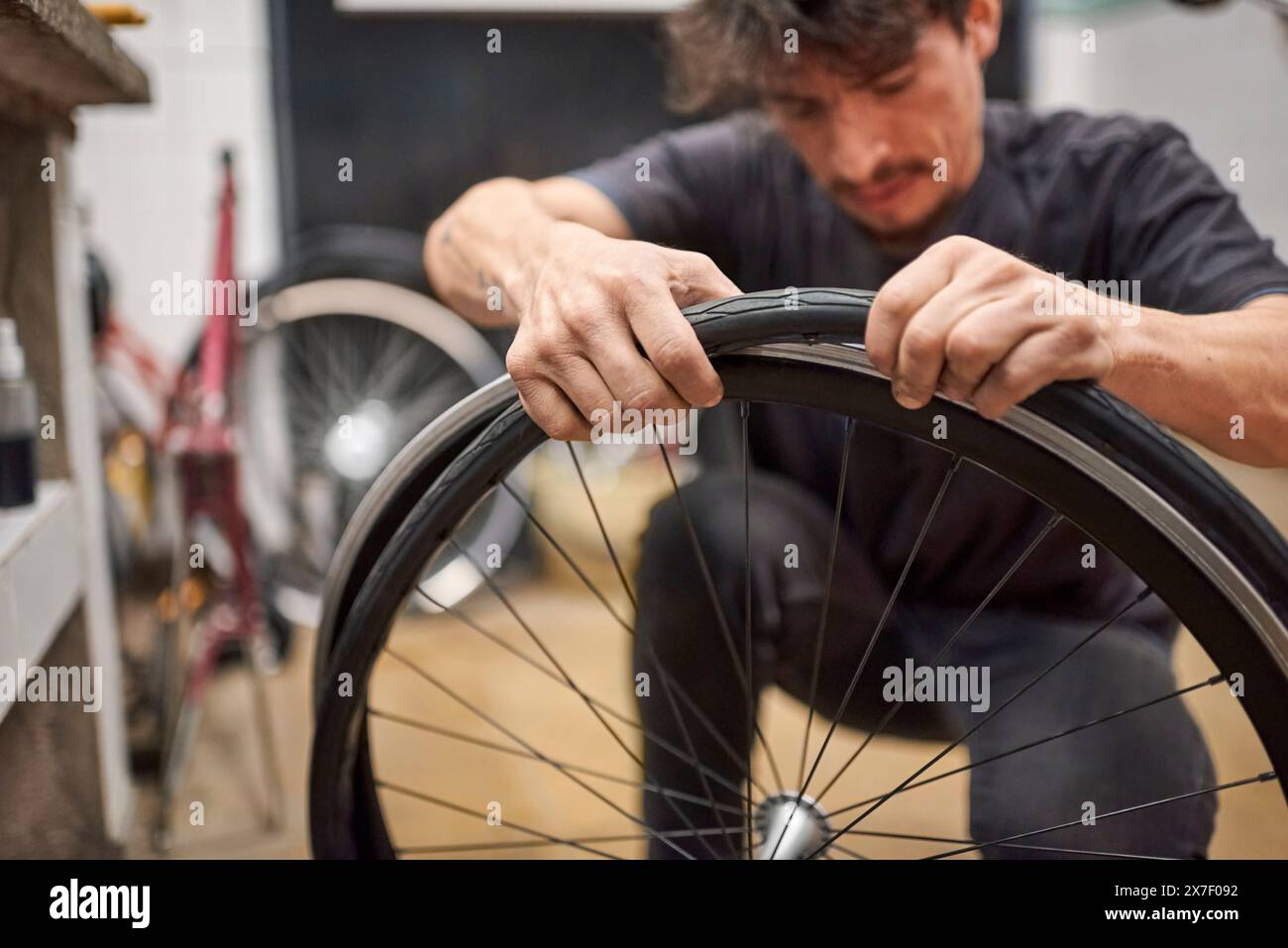 Latin bicycle repairman mounting an airless solid tire on a bike wheel ...