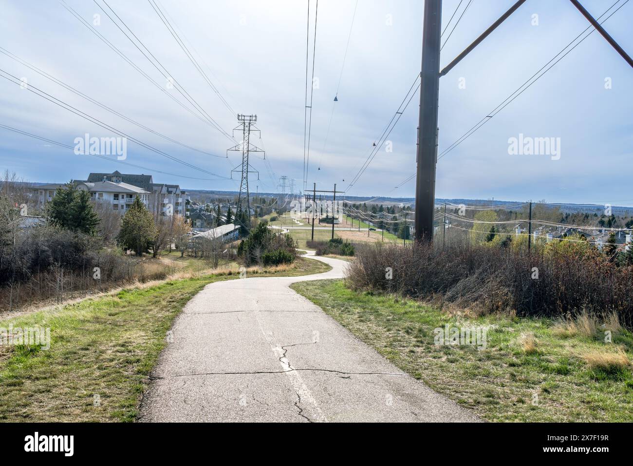 A winding paved park path under powerline through the city dwelling ...