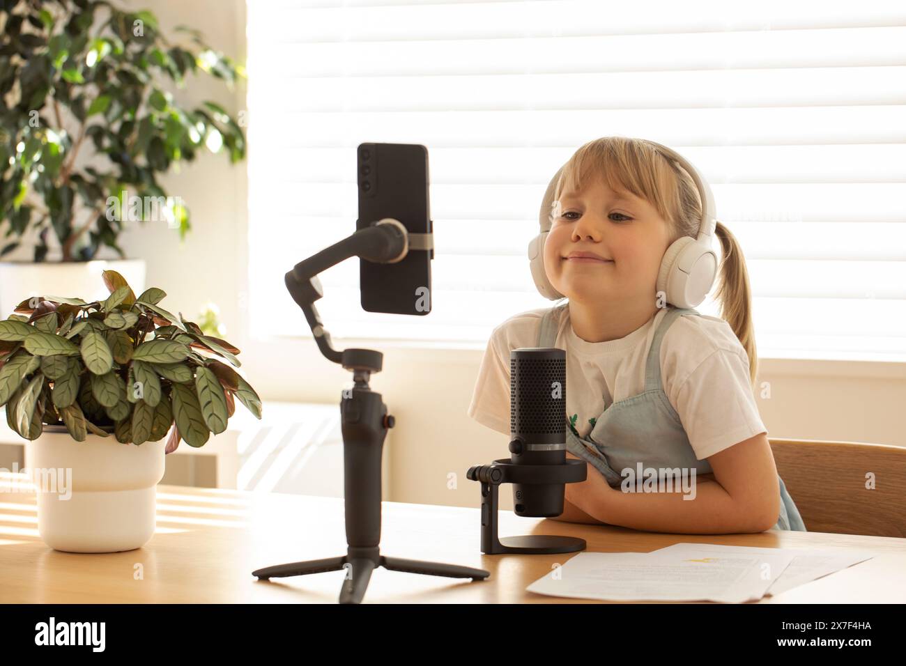 Young girl with headphones smiling during a solo podcast session ...