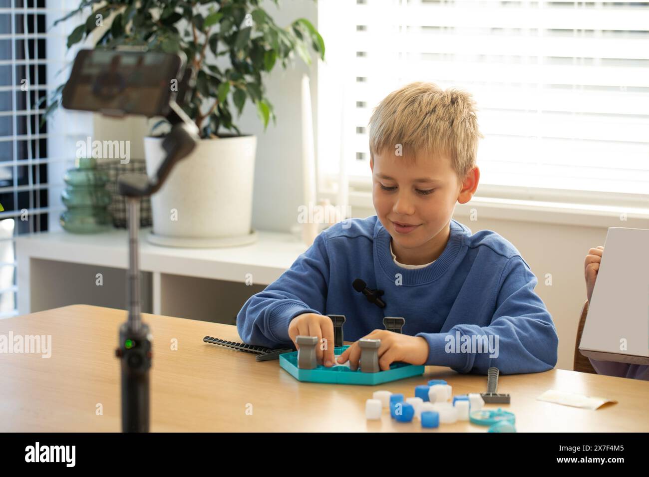 Boy plays a new board game for their blog, recording a fun and ...
