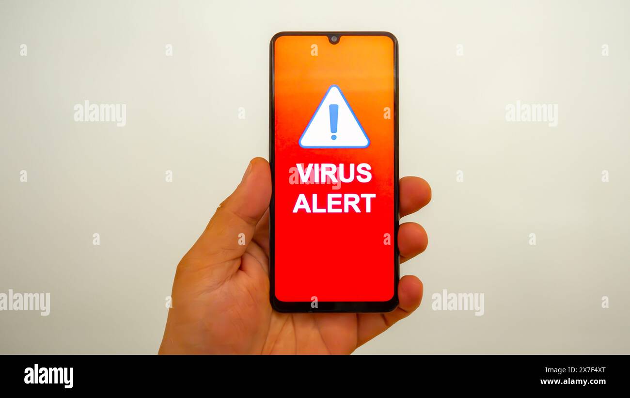 Man hand holding phone with warning virus alert alarm on screen ...