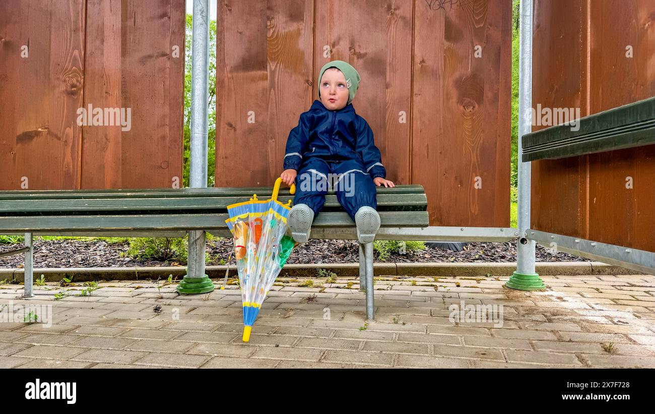 Children on a bus station, wear rubber boots and waterproof suit, with ...