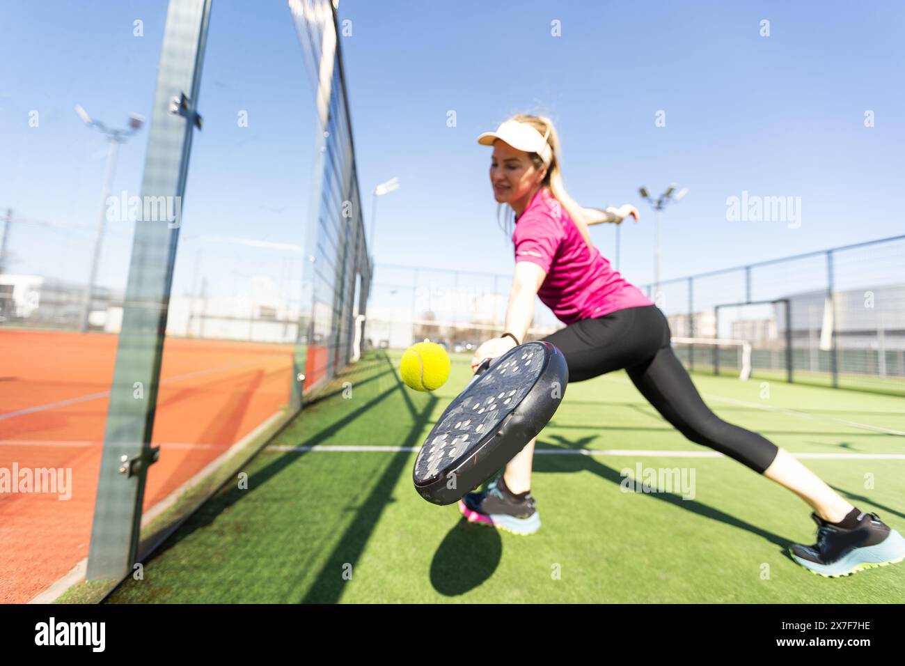 Active young woman trying to beat the ball by Padel racket while ...