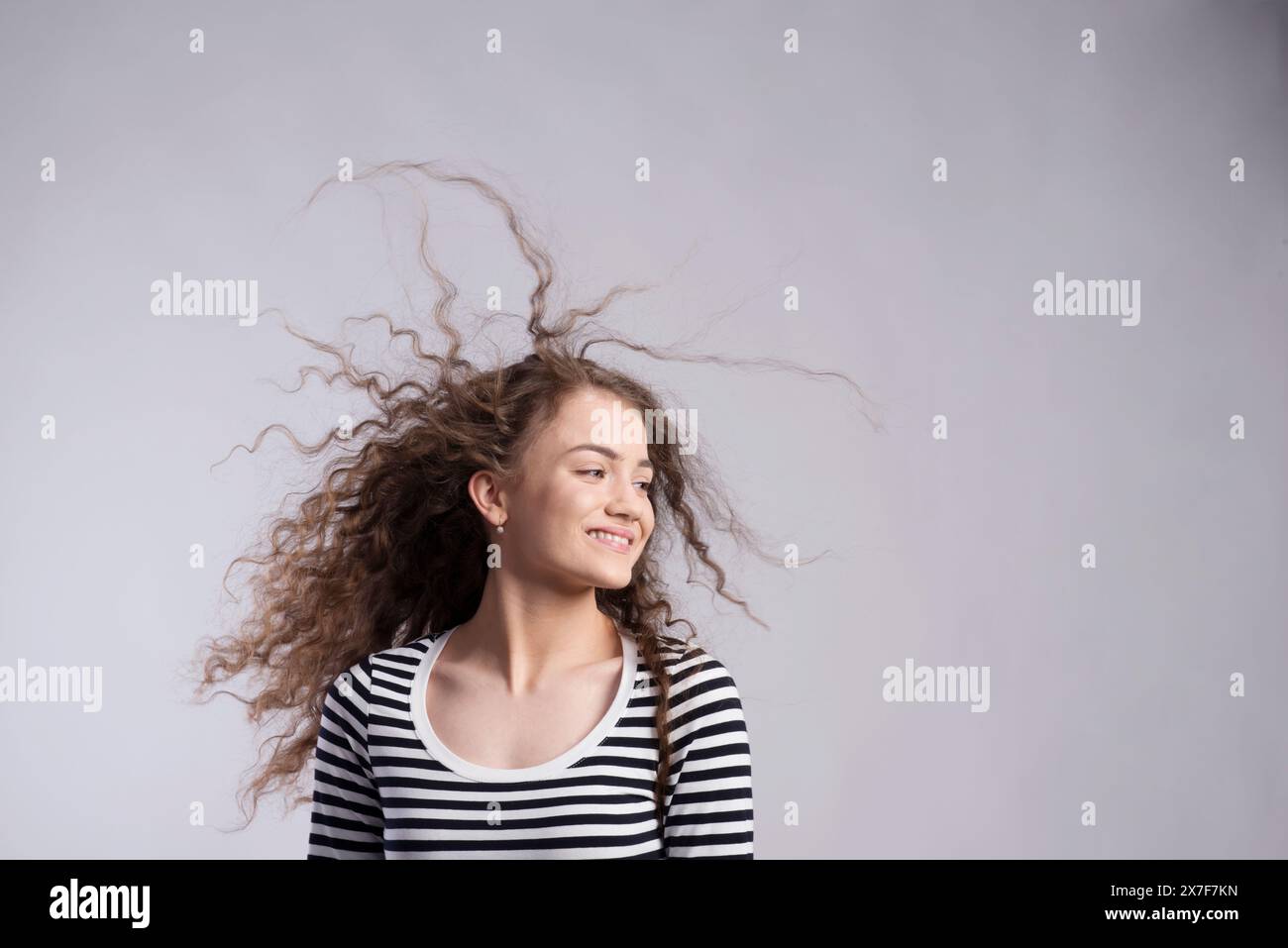 Portrait of a gorgeous teenage girl with curly hair, blowing in wind ...
