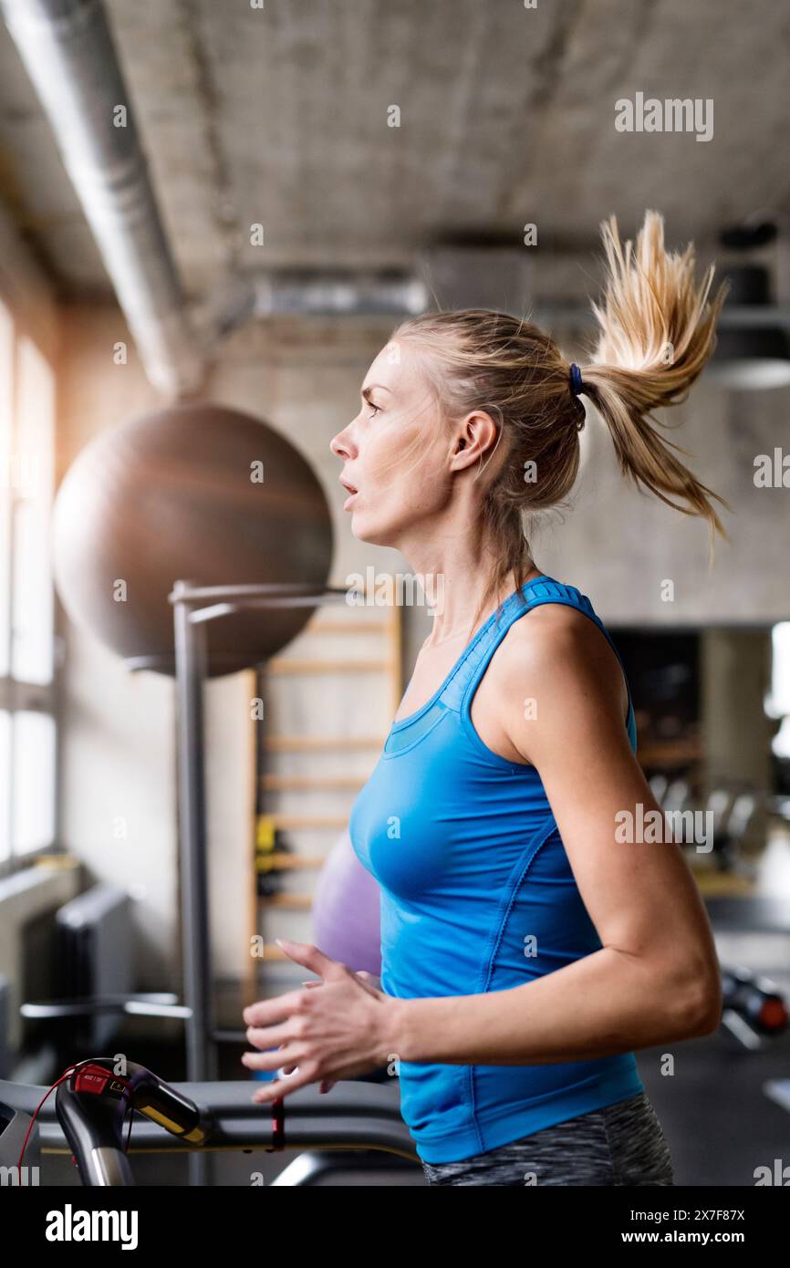 Beautiful sport woman in gym, running on treadmill. Routine workout for ...