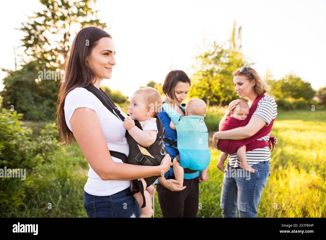 Mothers carrying babies in carriers, slings or wraps. Babywearing Stock ...