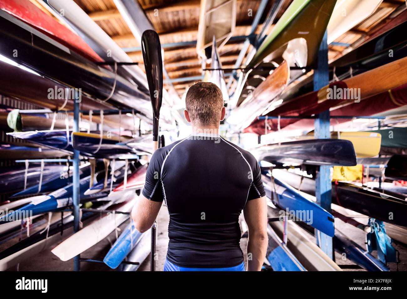 Portrat of young canoeist standing in the middle of stacked canoes ...