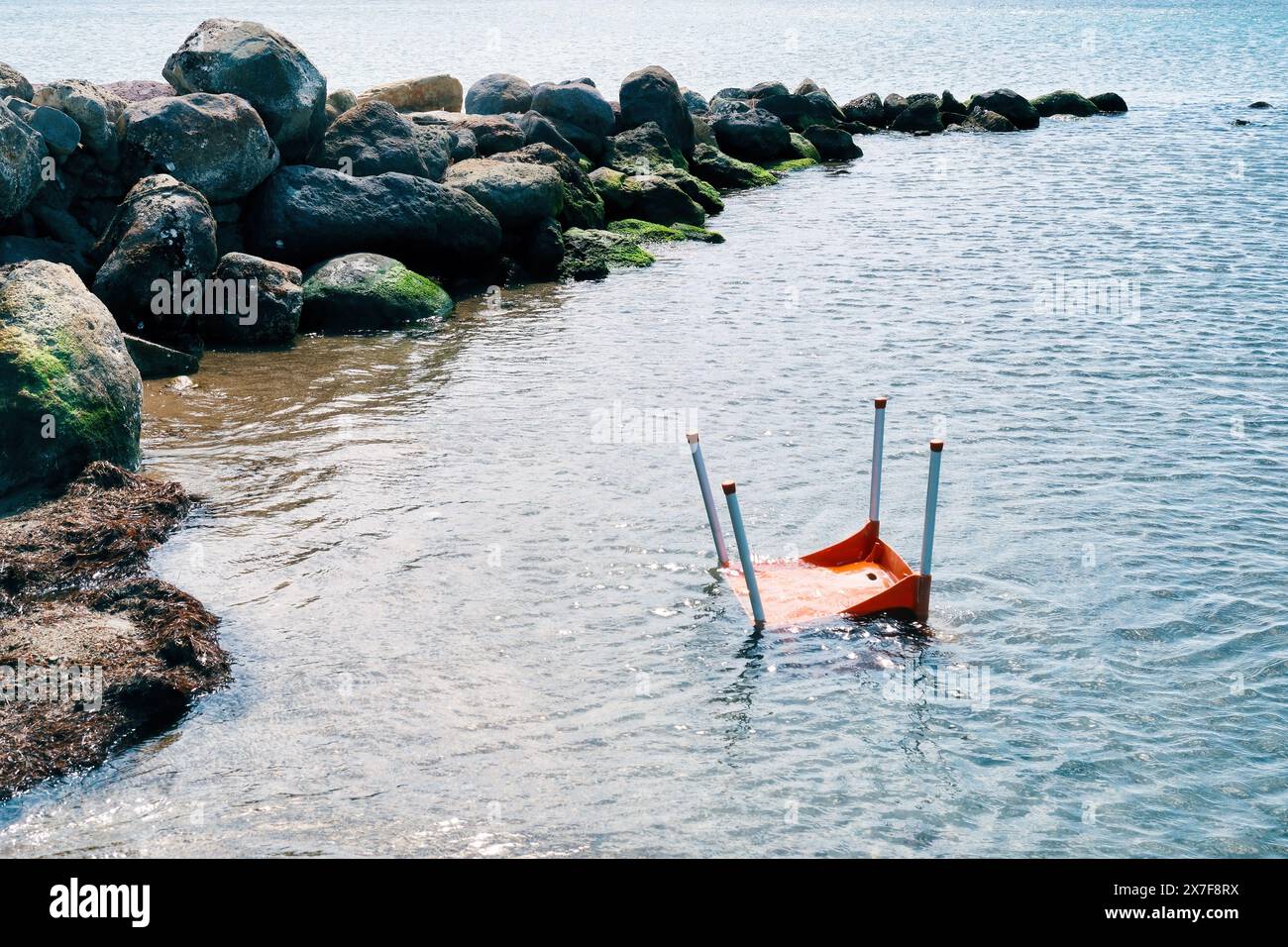 Overturned chair in the sea. Water pollution or plastic pollution ...