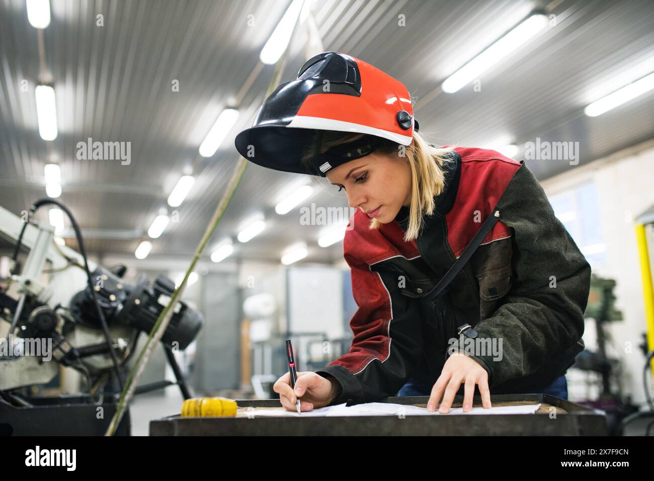 Beautiful blonde woman works as a welder in workshop, operating welding ...