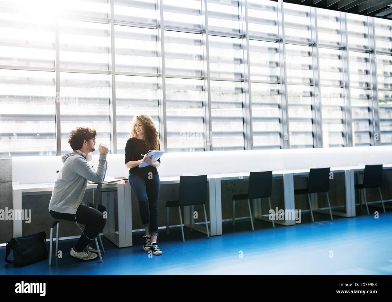 Young university students studying togeter in library, talking ...