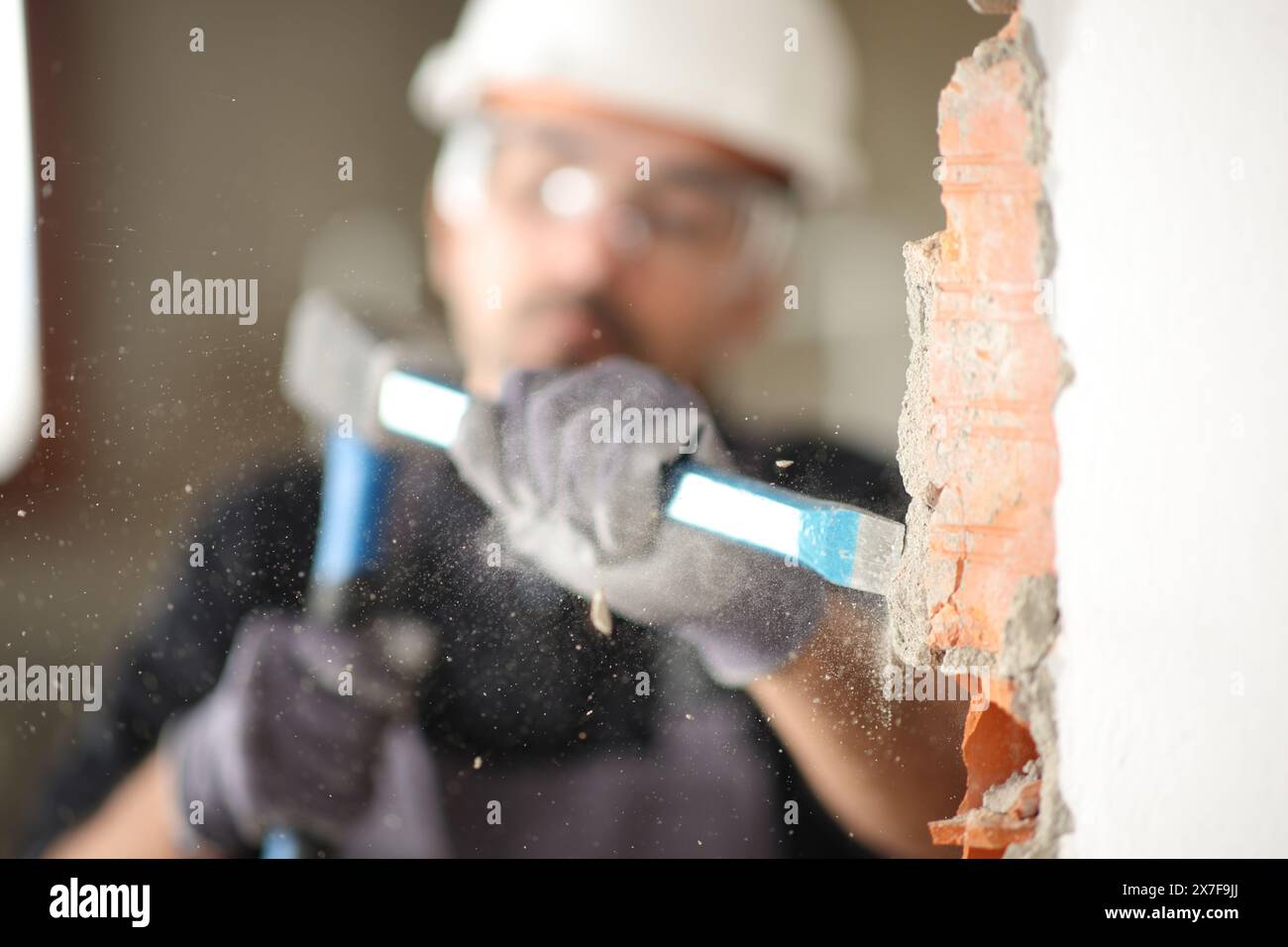 Construction worker using escarpment and hammer to wrek a wall in a ...